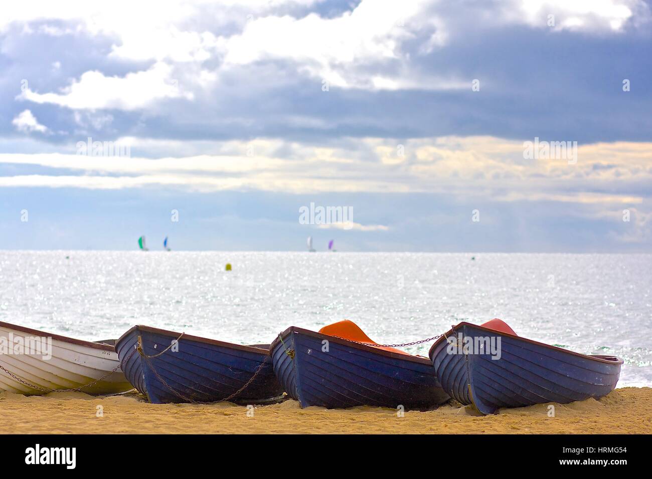 boats on a sandy beach with sparkling sea and sailing boats on the ...