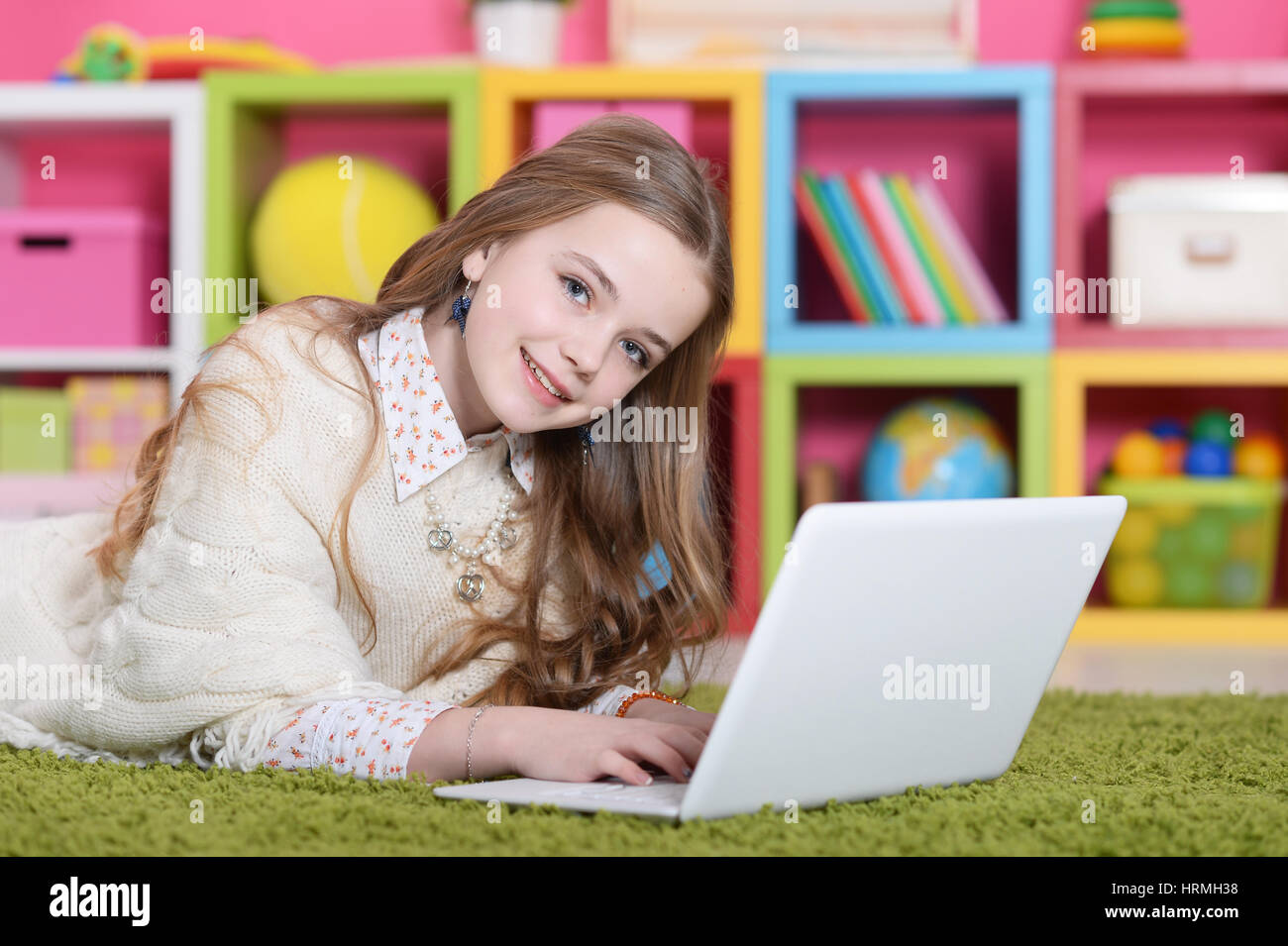 Girl with laptop lying on the carpet Stock Photo - Alamy