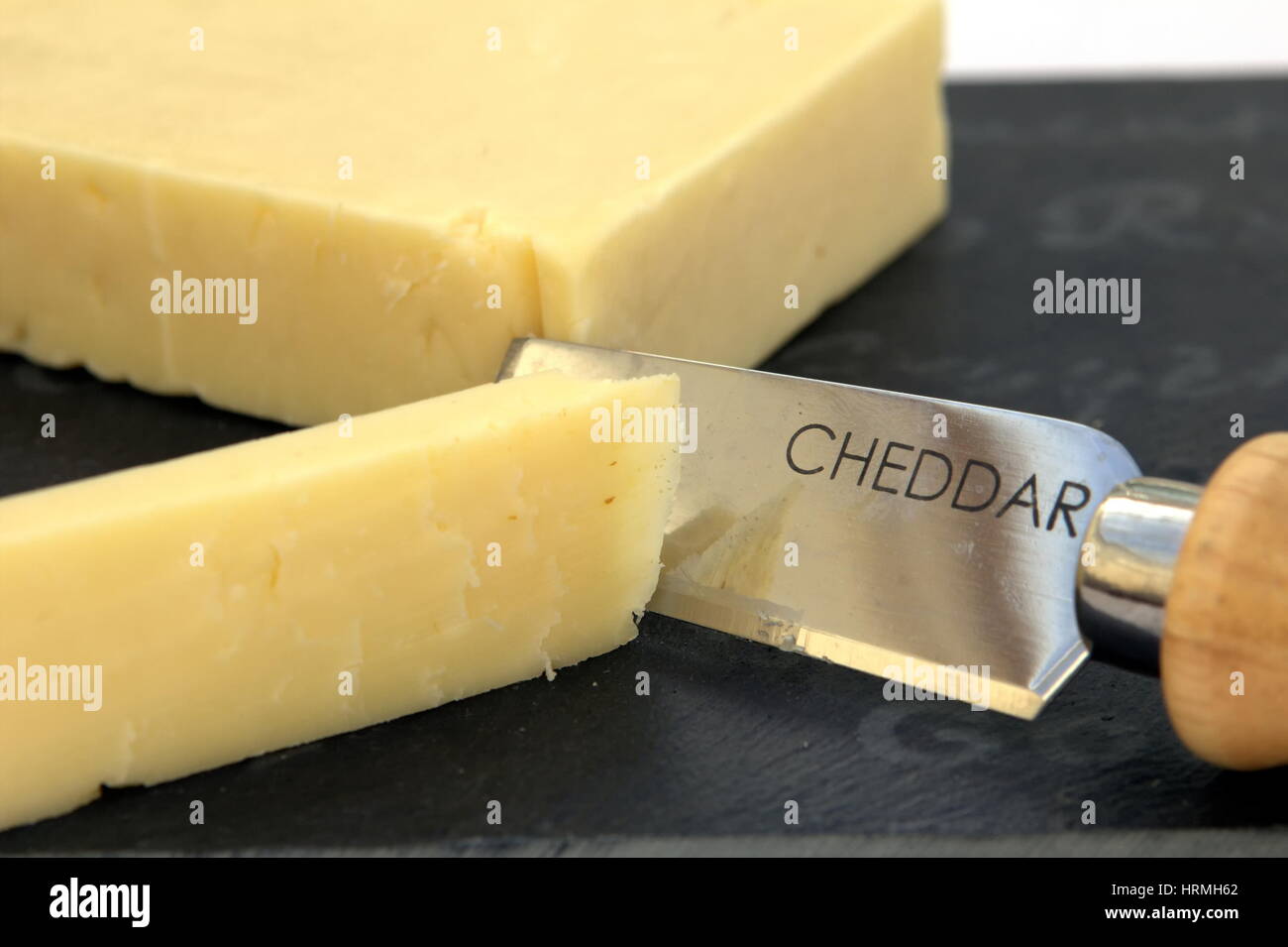 Fresh cut cheddar cheese on a slate board Stock Photo - Alamy