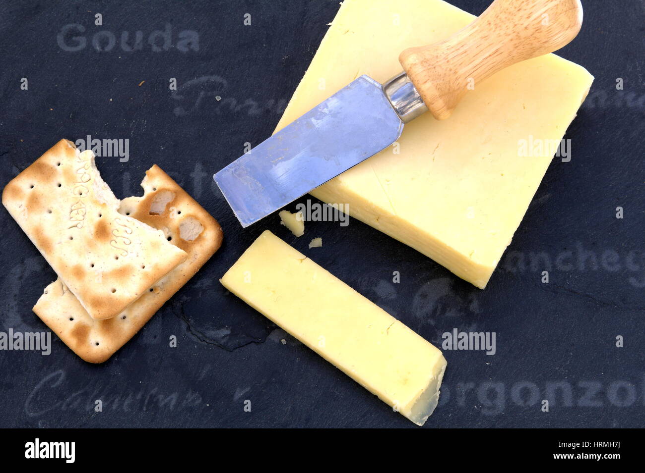 Fresh cut cheddar cheese with crackers on a slate board Stock Photo - Alamy