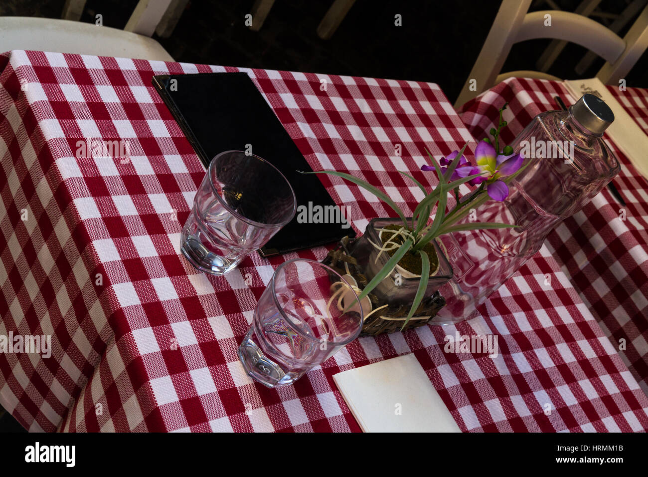 Exterior restaurant table with red checked tablecloth set ready for ...