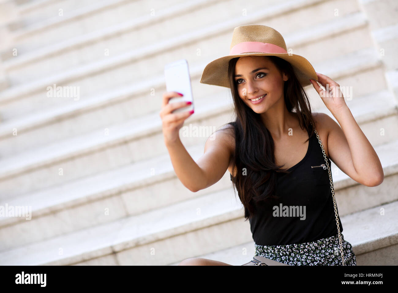 Young beautiful smiling woman in hat making selfie with smartphone ...