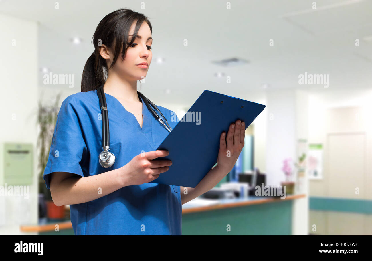 Beautiful young nurse reading some documents Stock Photo - Alamy