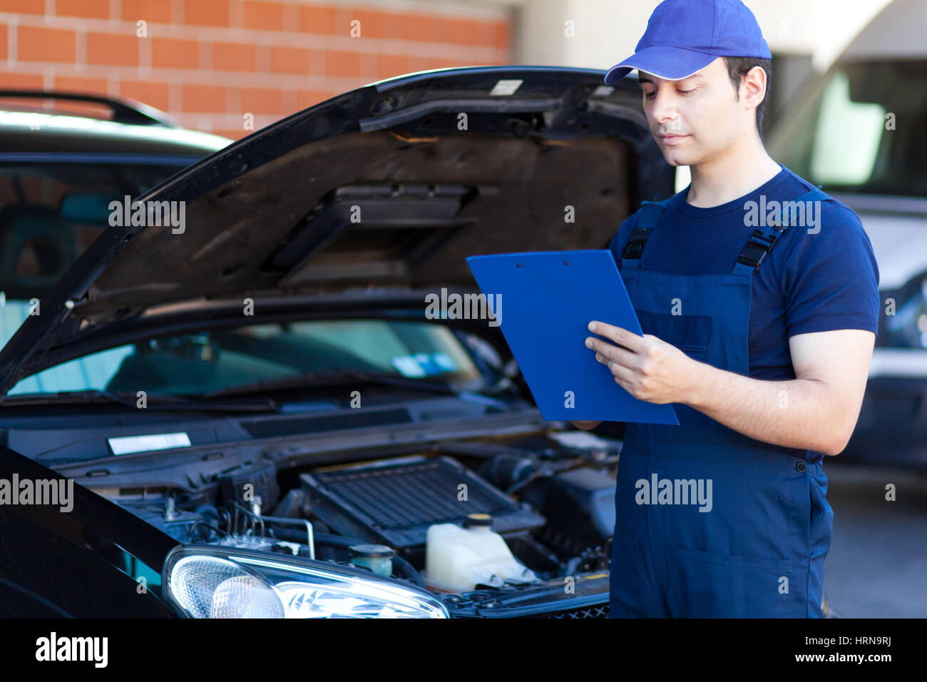 Mechanic writing on a clipboard Stock Photo - Alamy