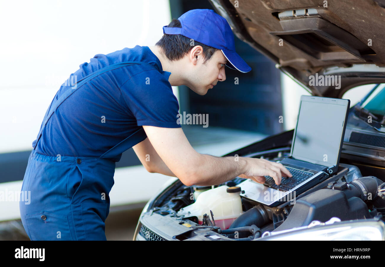 Mechanic using a laptop computer to check a car engine Stock Photo - Alamy