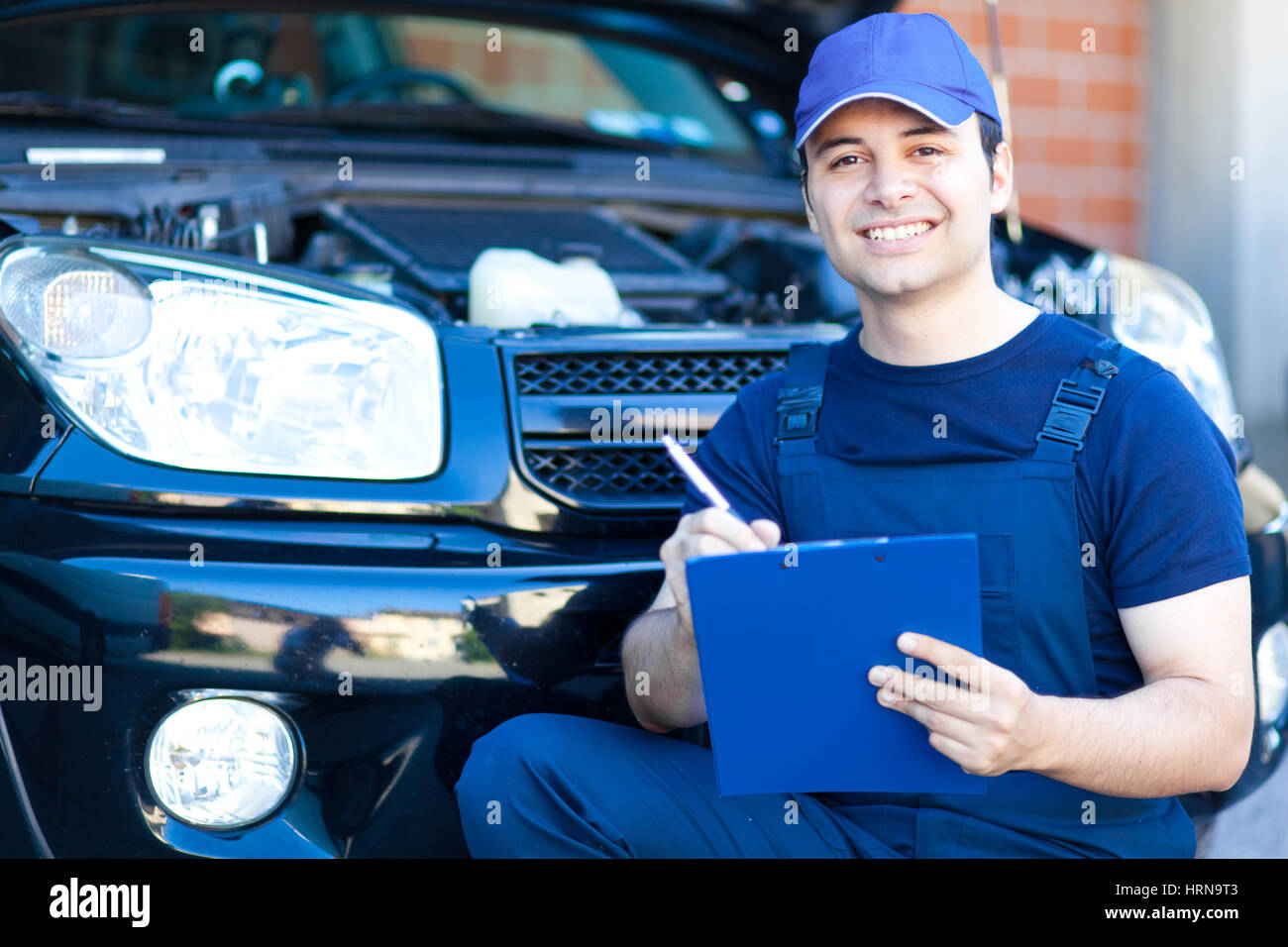 Mechanic writing on a clipboard Stock Photo - Alamy