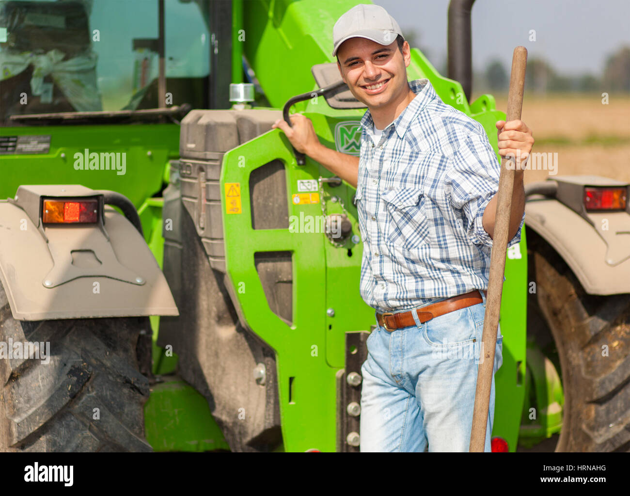 Portrait of a smiling farmer holding a pitchfork while working in his ...
