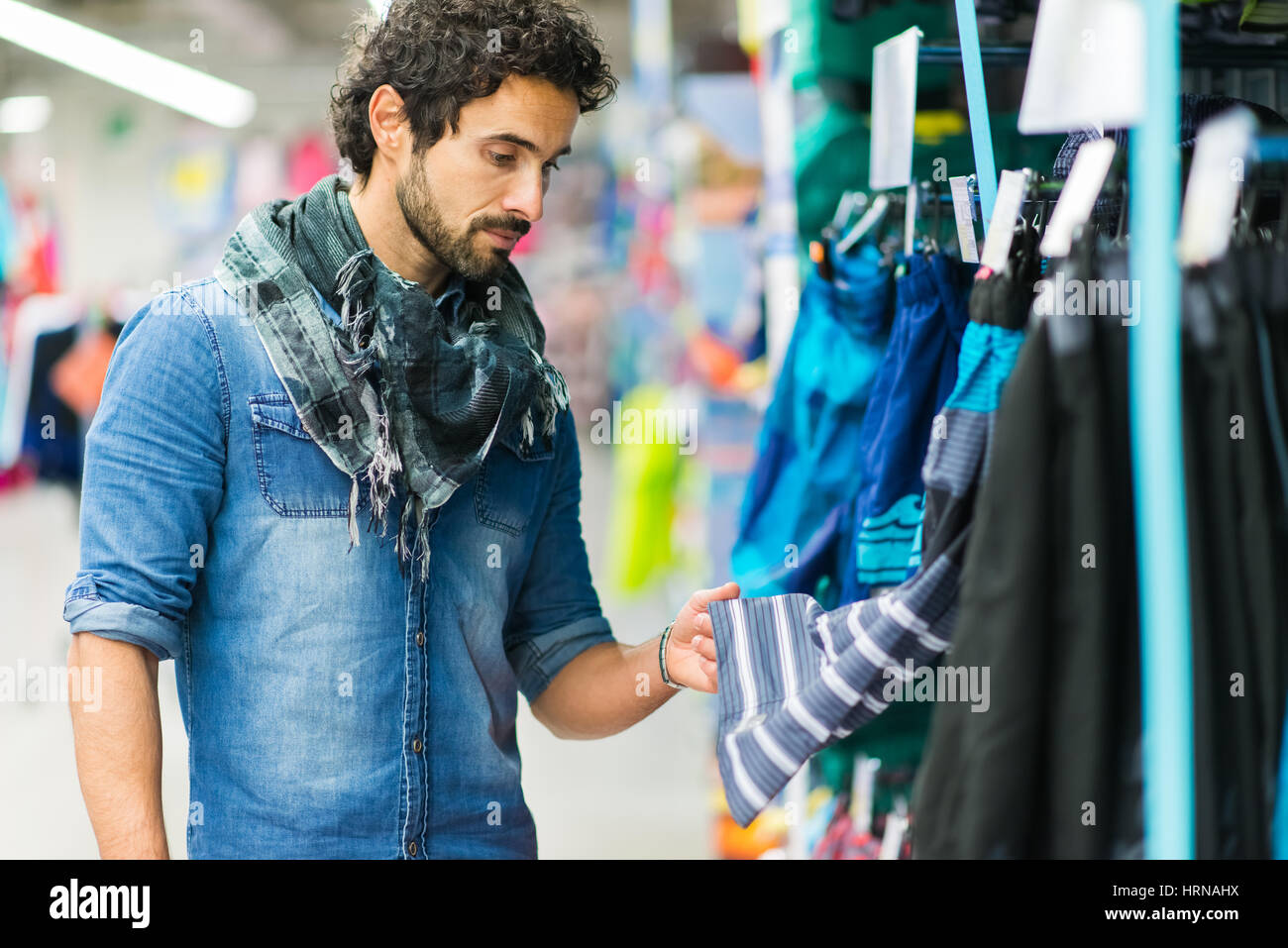 Handsome young man searching for clothes in a shop Stock Photo - Alamy
