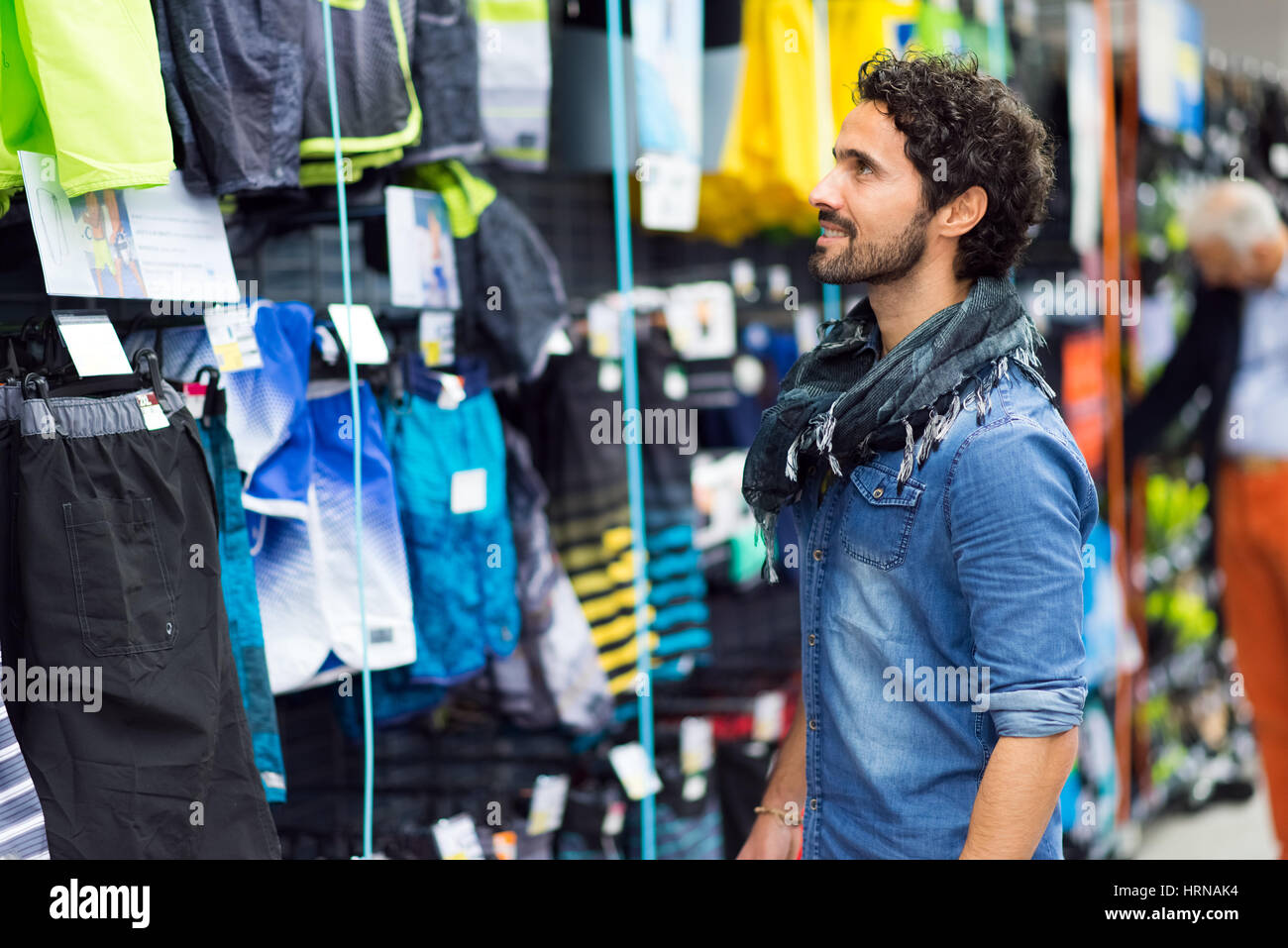 Handsome young man searching for clothes in a shop Stock Photo - Alamy
