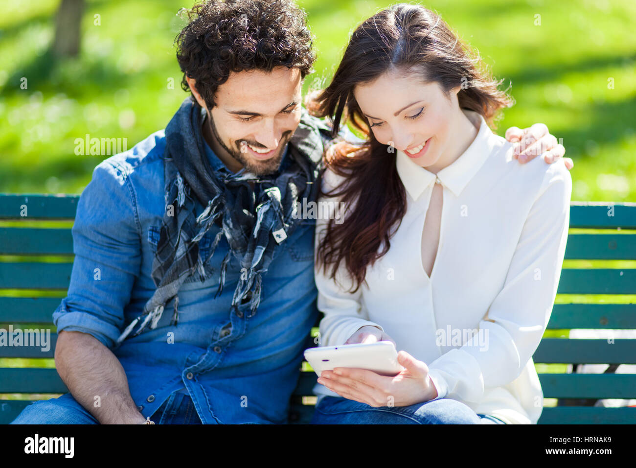 Happy Couple Using Tablet Computer On Bench Outdoor Stock Photo - Alamy