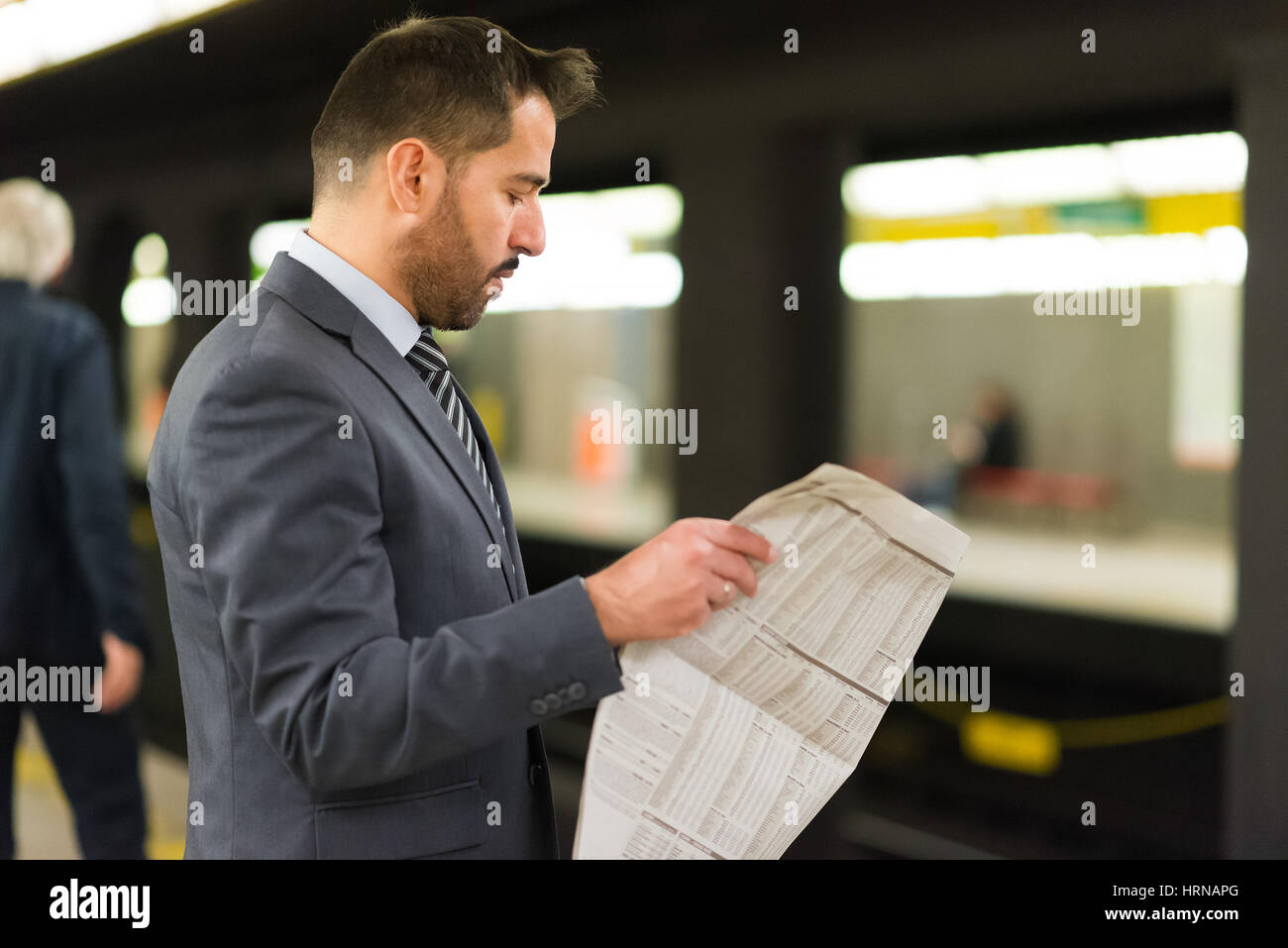 Commuter reading a newspaper while waiting for the subway train Stock ...