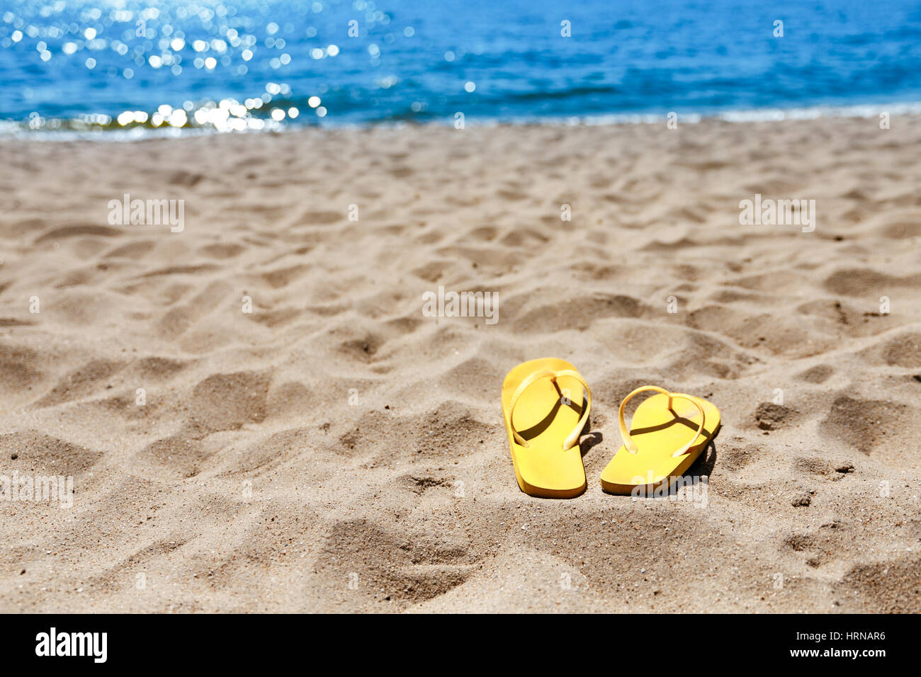 Yellow beach slippers on sandy beach, summer, bathing Stock Photo - Alamy