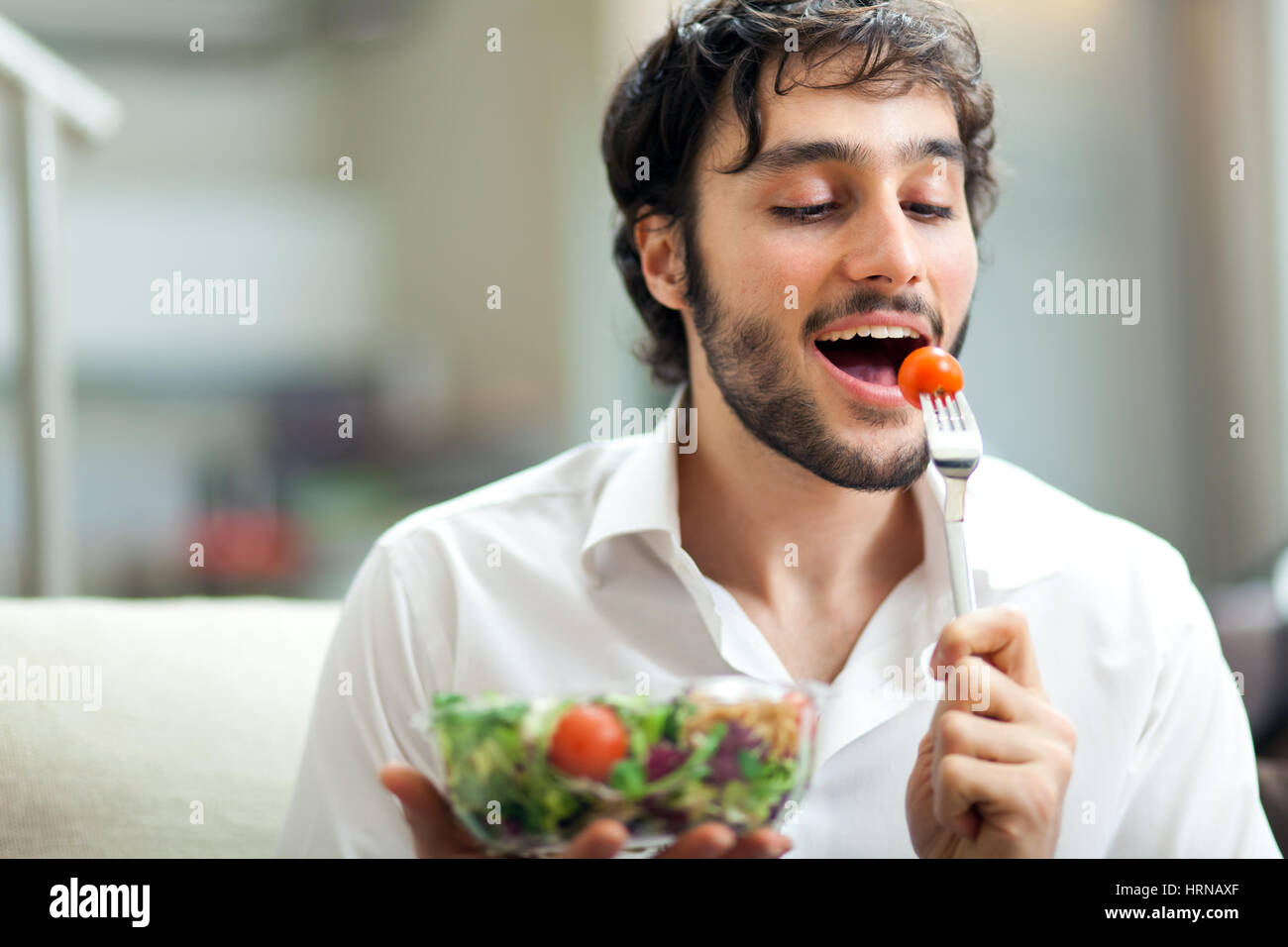 Young man eating a salad Stock Photo - Alamy