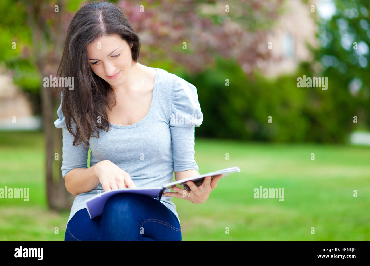 Smiling student outdoor reading a book Stock Photo - Alamy