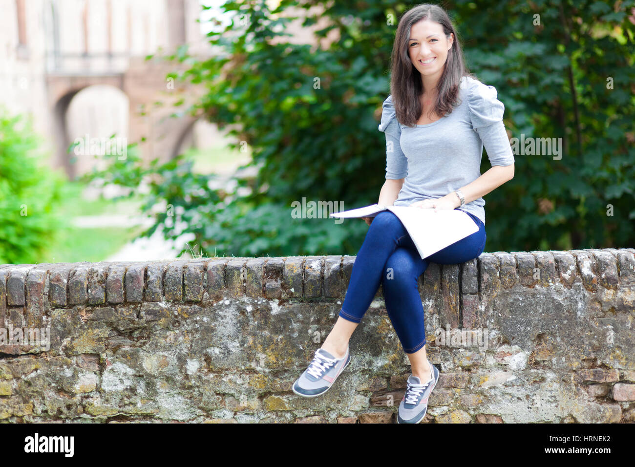 Young beautiful female student reading a book outdoor Stock Photo - Alamy