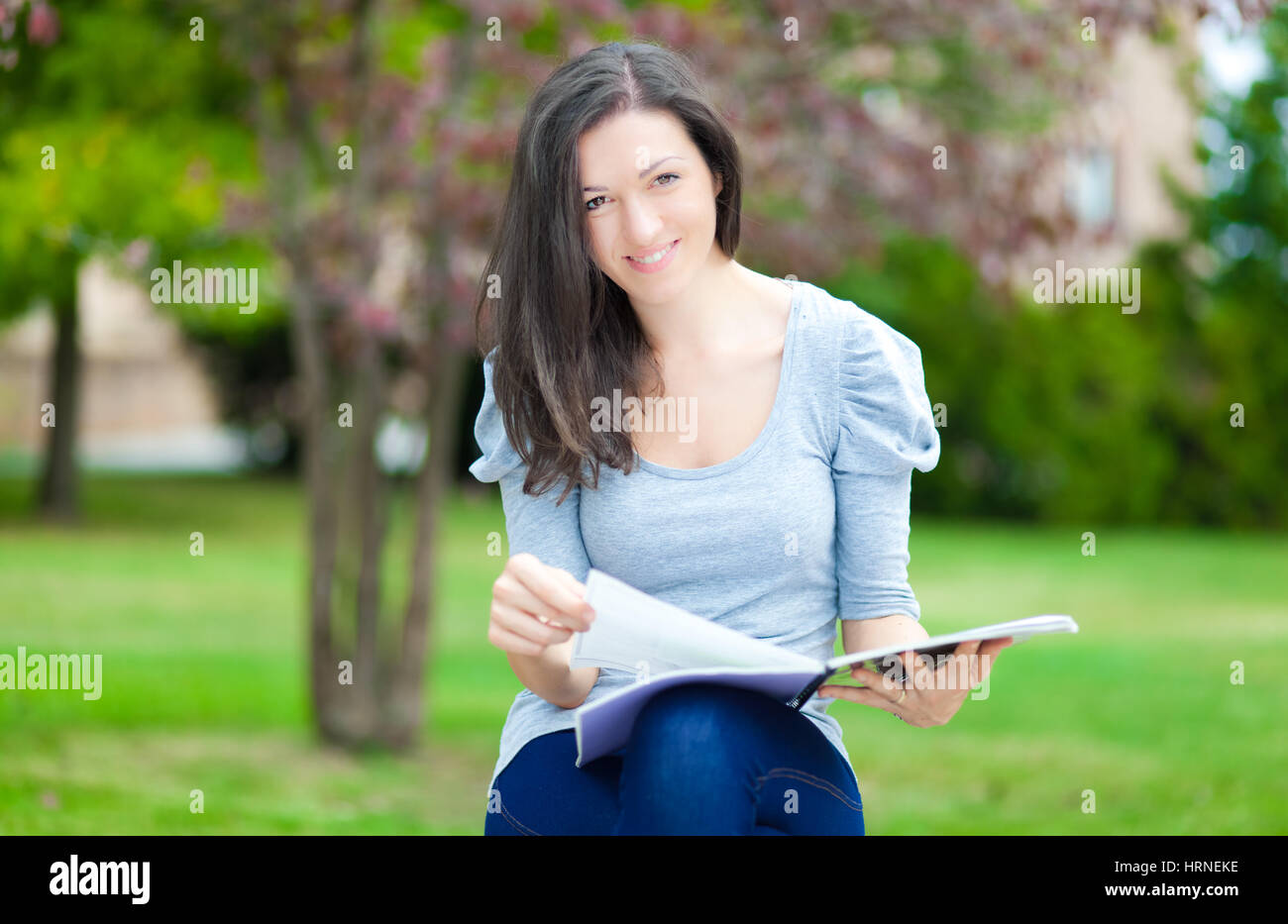 Young beautiful female student reading a book outdoor Stock Photo - Alamy