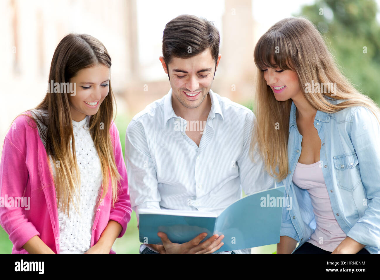 Smiling students reading a book outdoor Stock Photo - Alamy