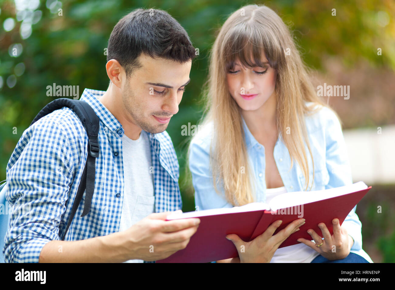 Couple of students reading a book outdoor Stock Photo - Alamy