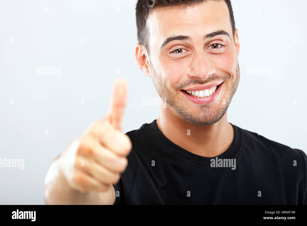 Smiling young man showing thumbs up Stock Photo - Alamy