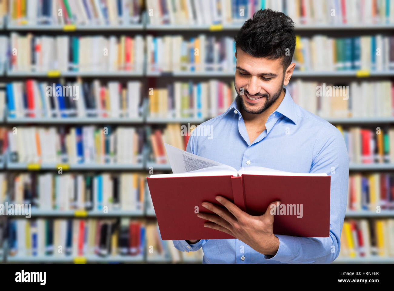 Young man reading a book in a library Stock Photo - Alamy