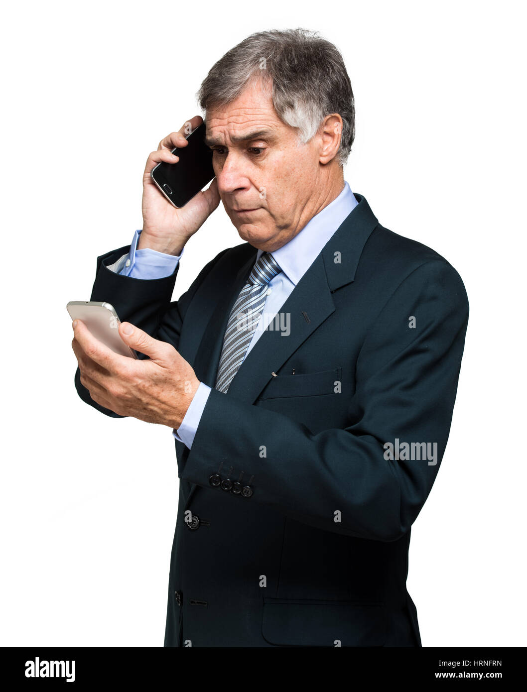 Worried businessman talking at the phone while looking to another phone ...