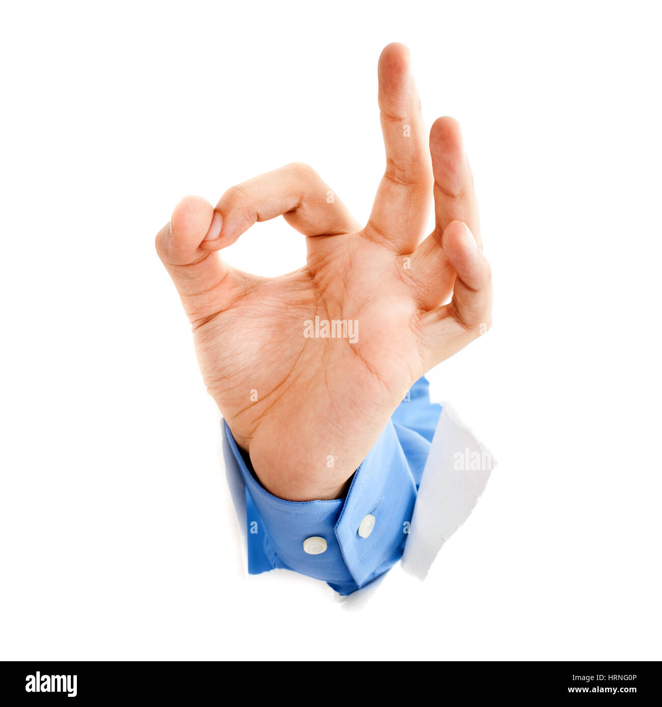 Hand giving ok sign from a ripped hole in a white paper background ...