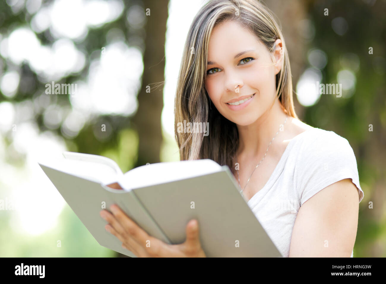 Beautiful girl reading a book at the park Stock Photo - Alamy