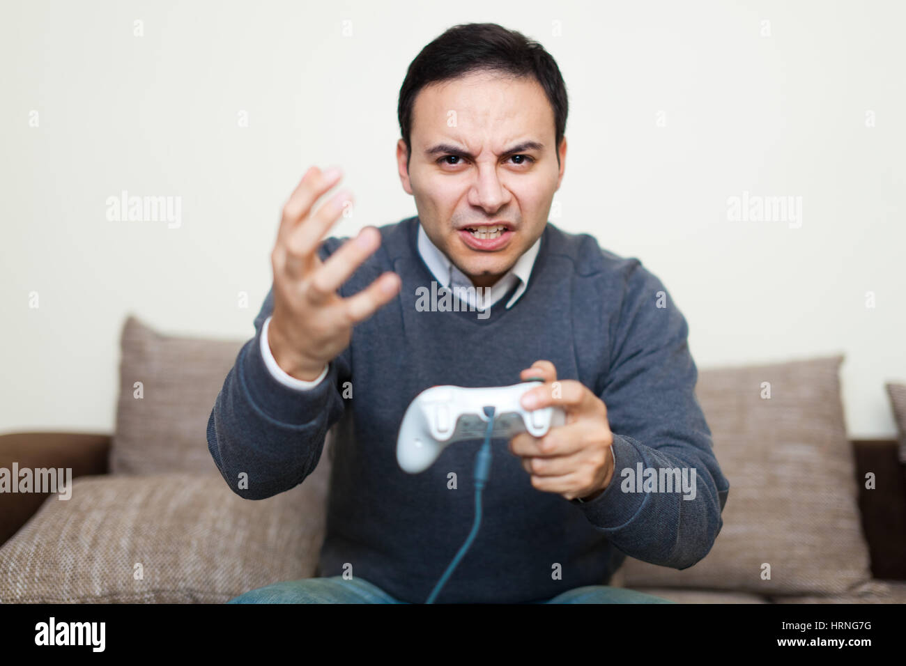 Angry man playing videogames on his sofa Stock Photo - Alamy