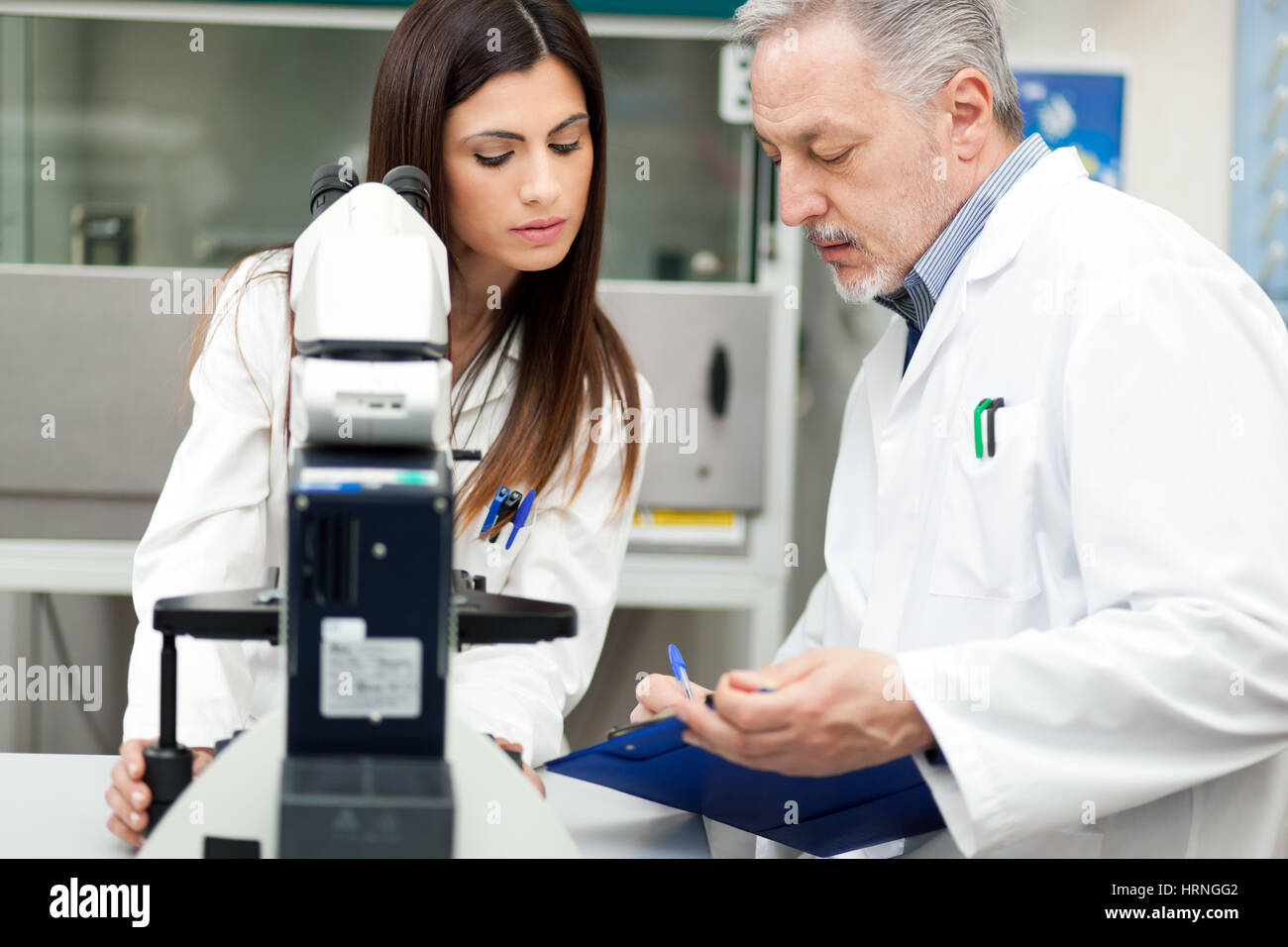 Couple of Scientist using a microscope in a laboratory Stock Photo - Alamy