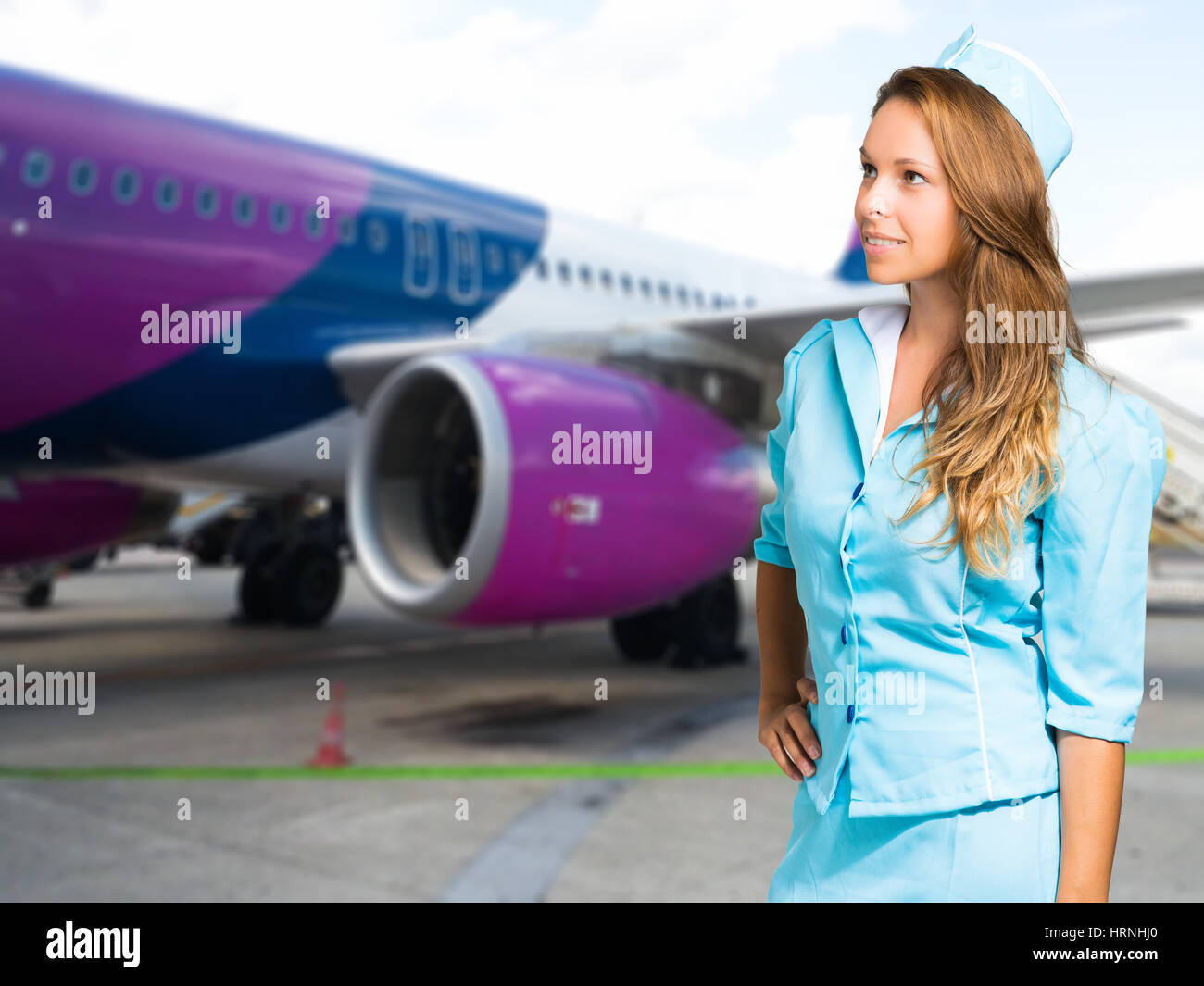 Smiling hostess with airplane on the background Stock Photo - Alamy