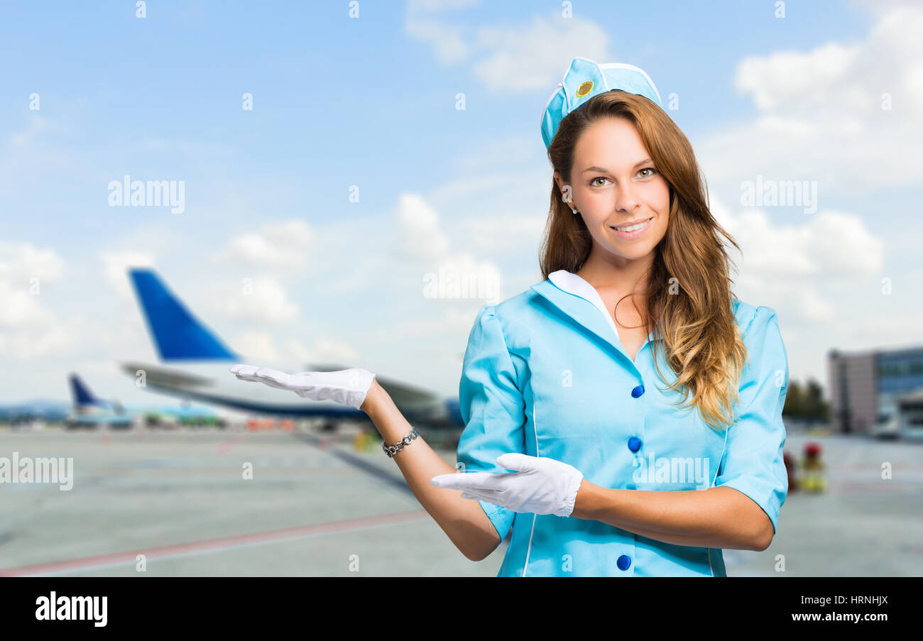 Smiling hostess with airplane on the background Stock Photo - Alamy