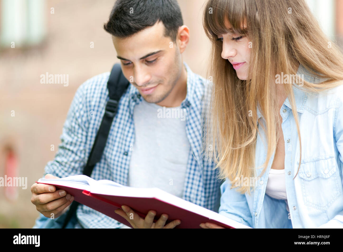 Couple of students reading a book Stock Photo - Alamy