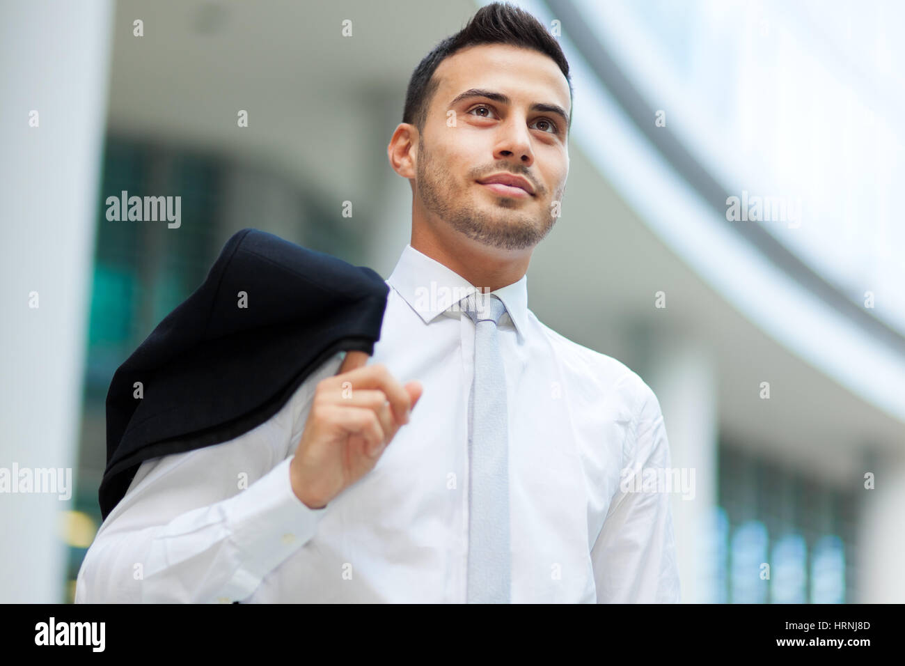 Confident young businessman outdoor holding his jacket Stock Photo - Alamy