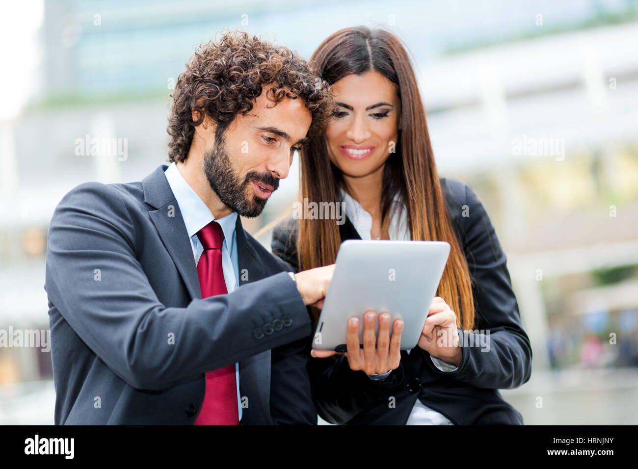 Two business people outdoor using a tablet Stock Photo - Alamy