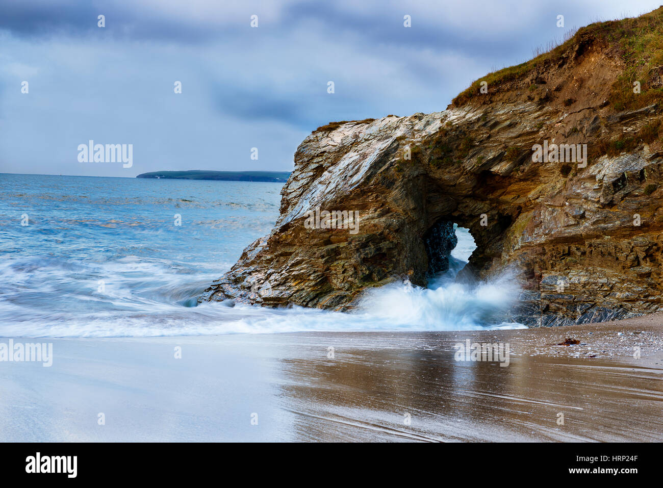 A gap in the rocky cliff section at Spit beach, Cornwall creates a huge ...