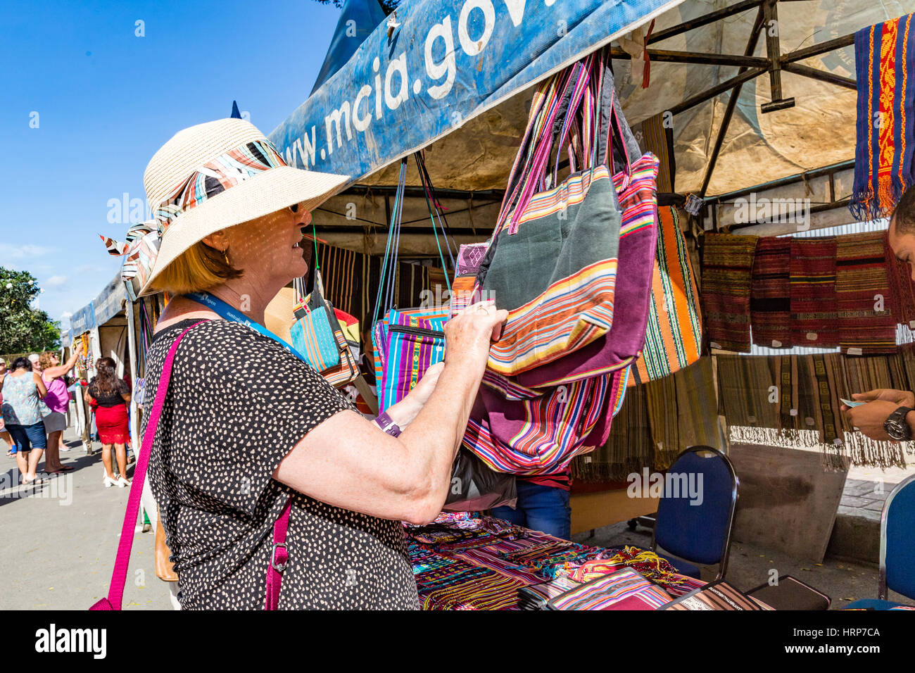 A female tourist inspects goods at a traditional street craft market in ...