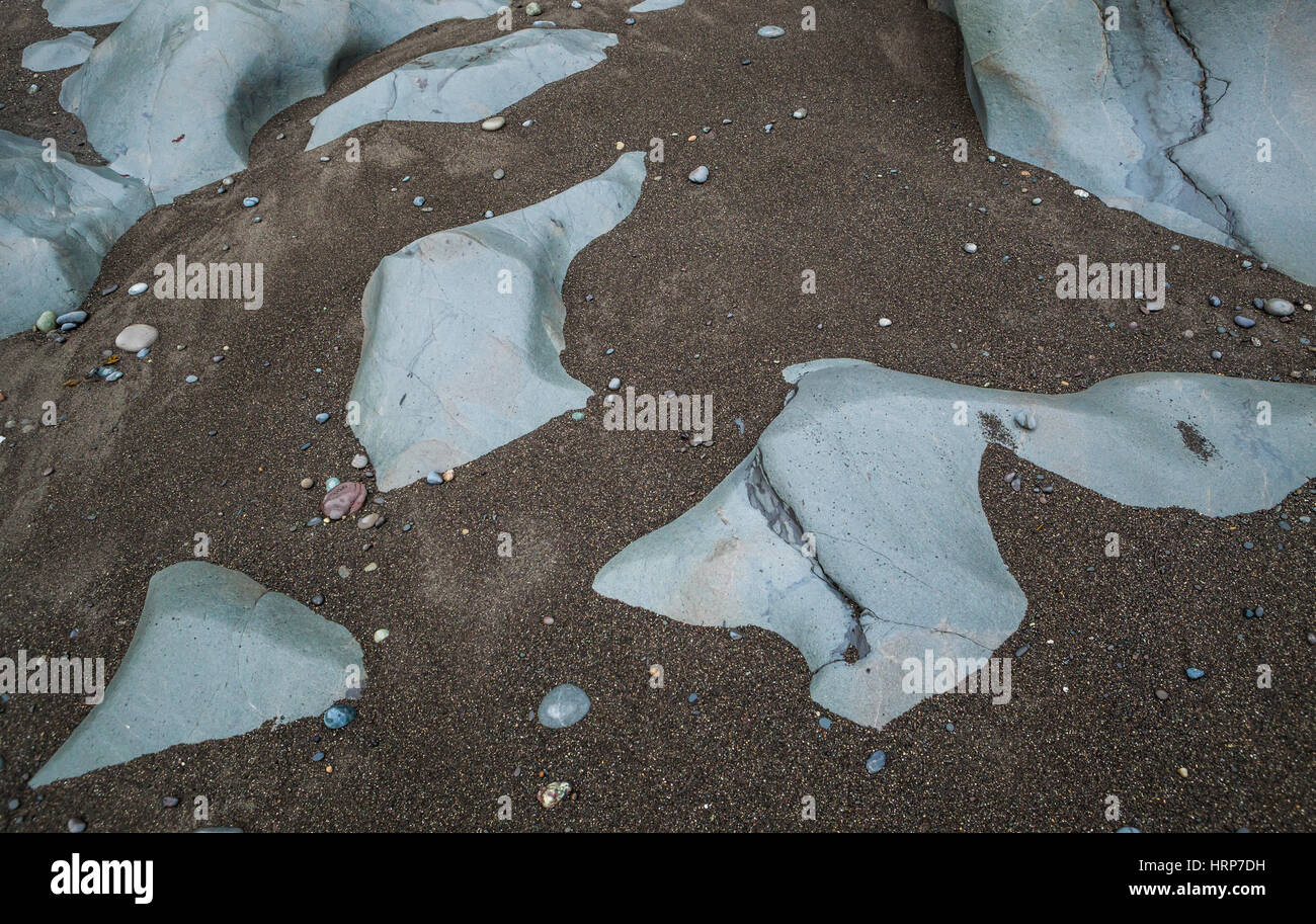 Rocks and sand on a beach at low tide Stock Photo - Alamy