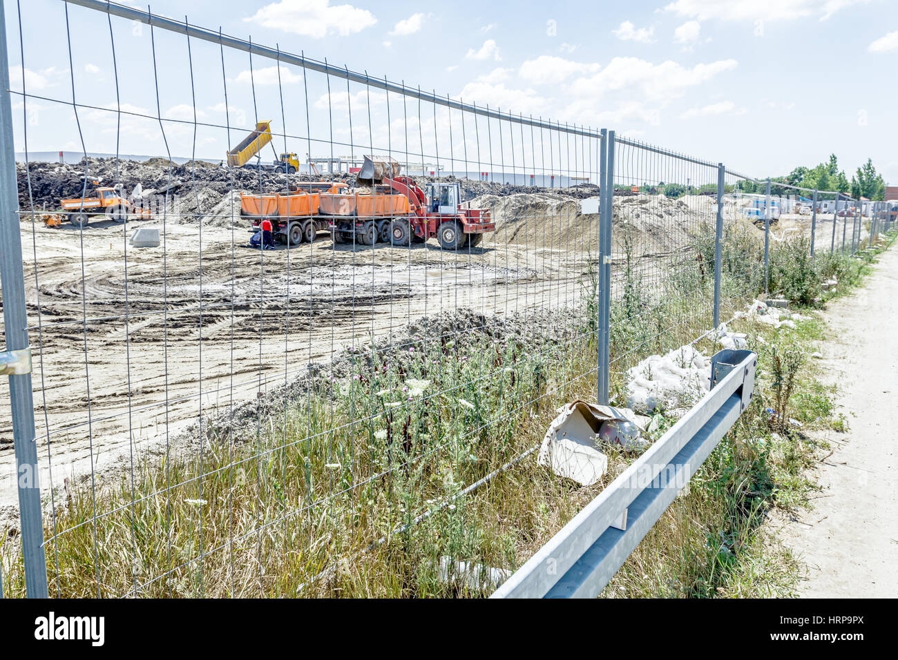 View through a fence wire on big loader until is filling a dump truck ...