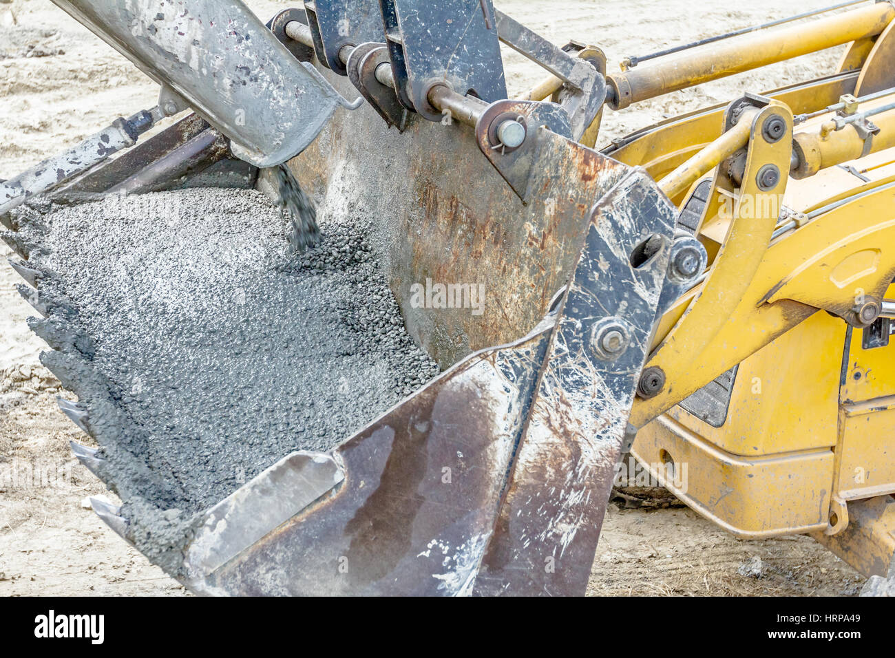Concrete mixer truck is pouring fresh concrete into excavator bucket at ...