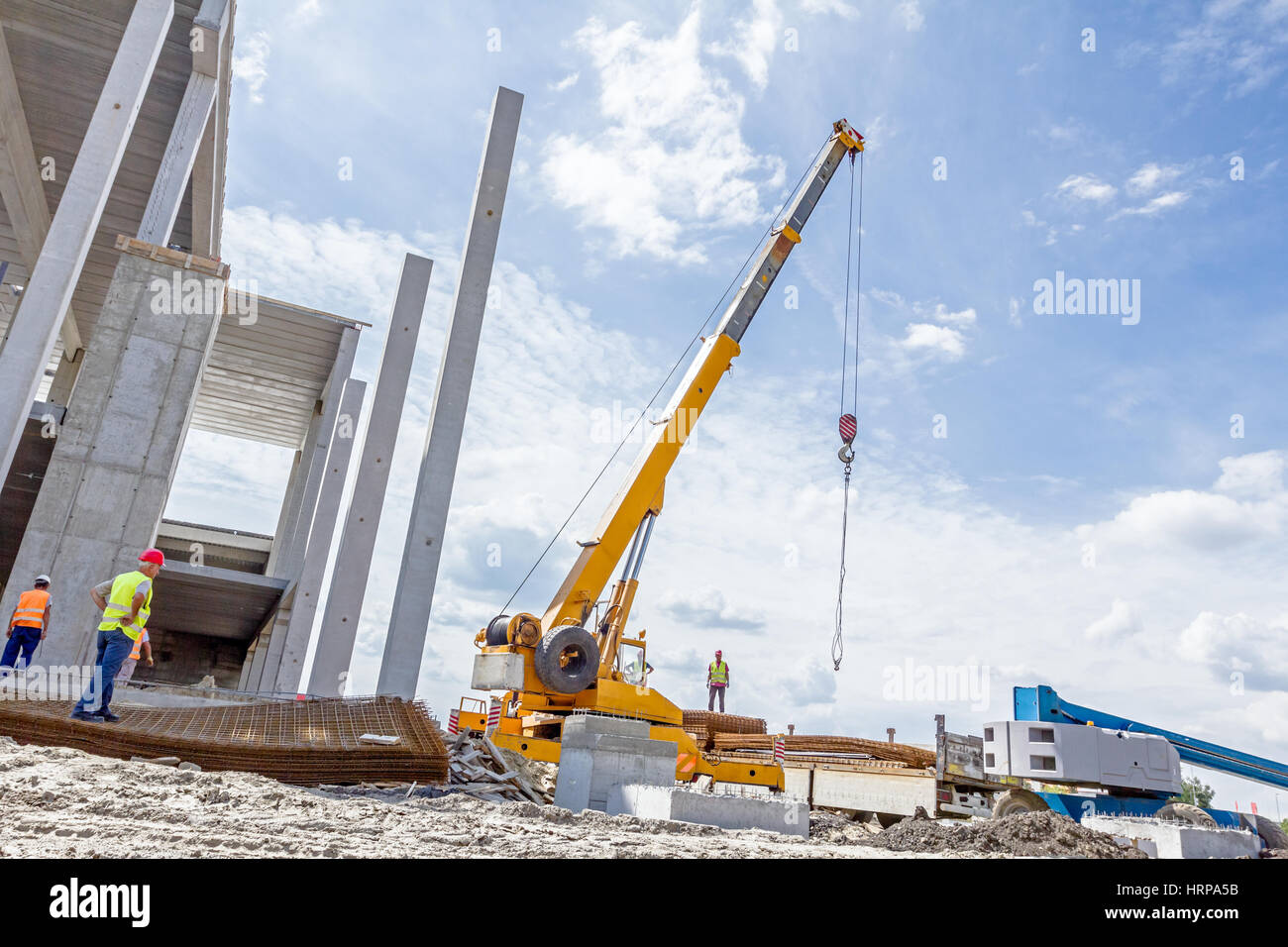 Mobile crane is unloading reinforcing mesh from truck trailer. Workers ...