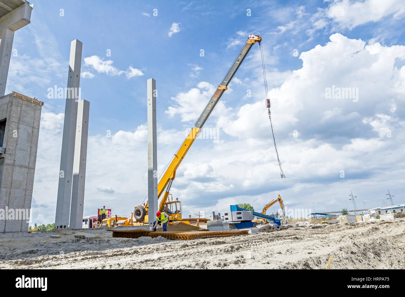 Mobile crane is unloading reinforcing mesh from truck trailer. Workers ...