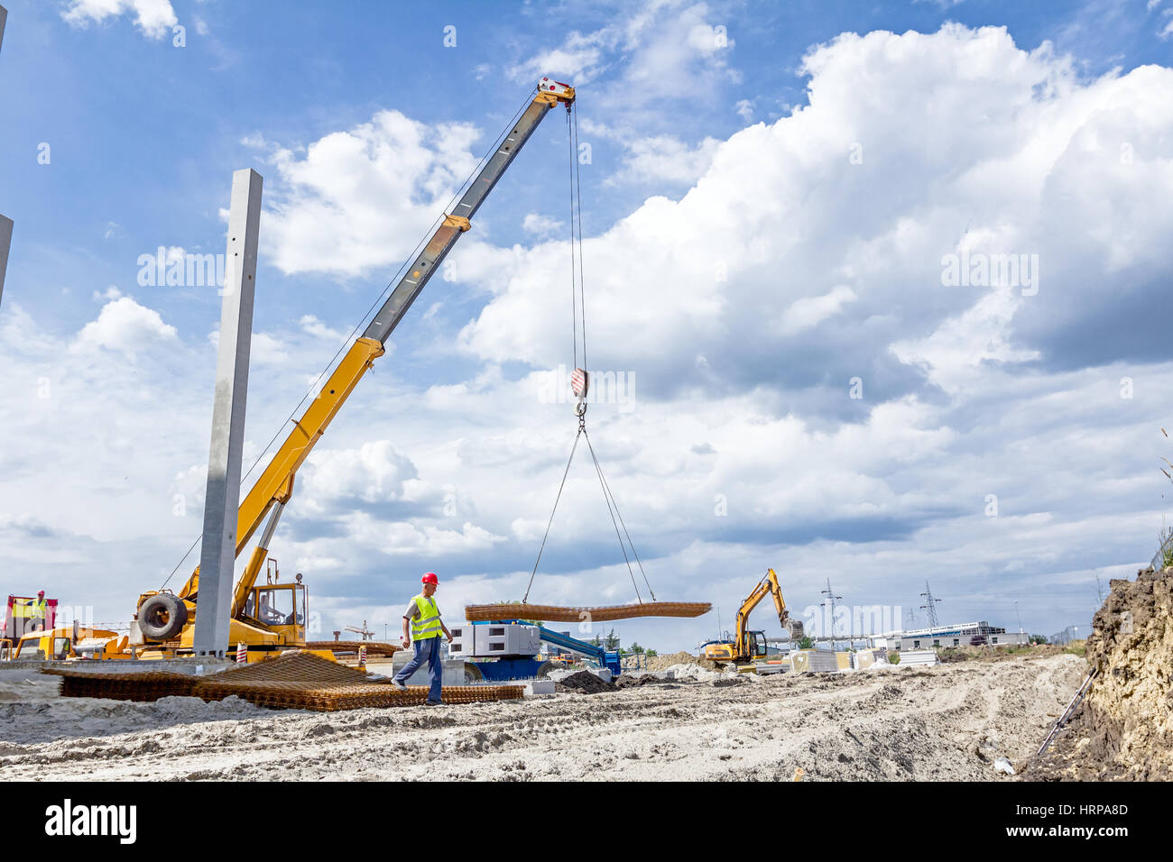 Mobile crane is unloading reinforcing mesh from truck trailer. Workers ...
