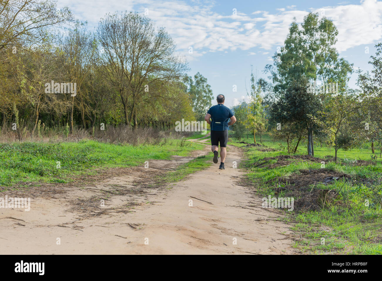 Big belly man jogging , exercising, doing cardio in the park , slightly ...