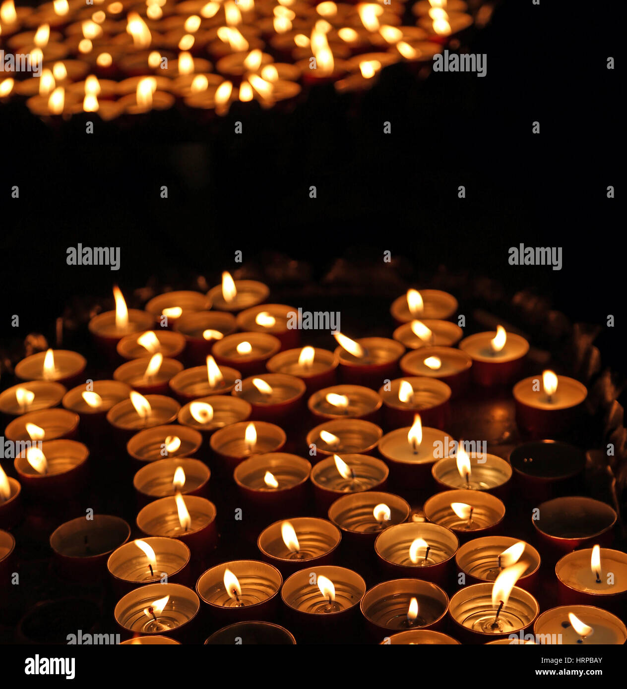 many candles lit with the warm flame during the religious ceremony ...