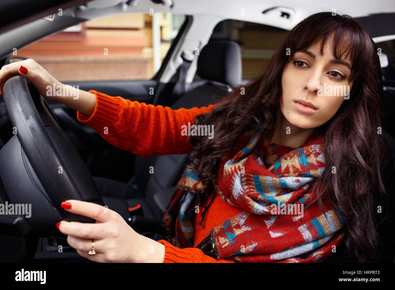 Woman in coloured scarf and orange sweater driving a car Stock Photo ...