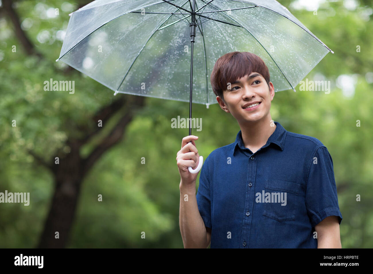 Young man holding umbrella Stock Photo - Alamy
