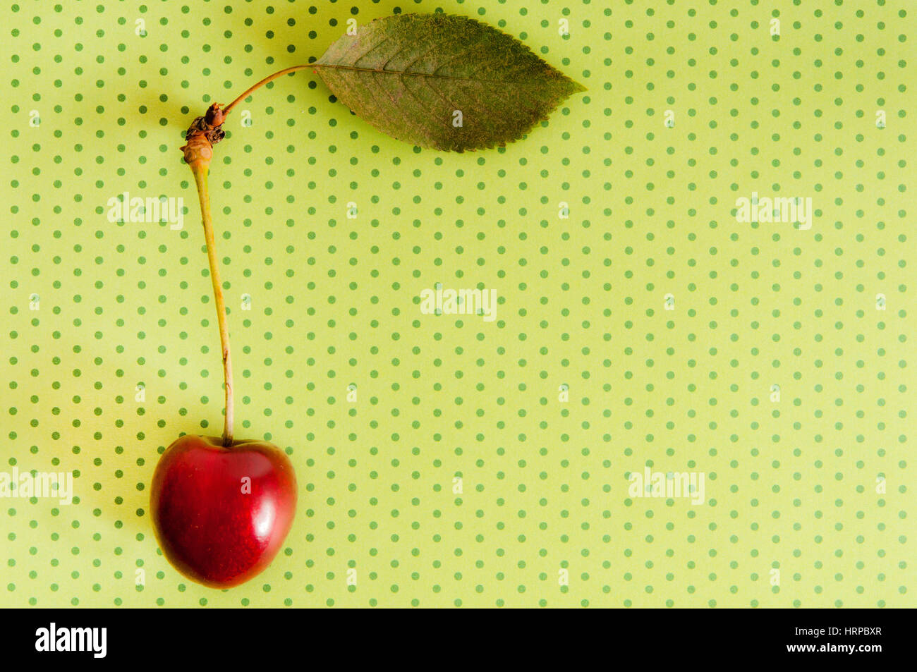 one red cherry on a retro background Stock Photo - Alamy