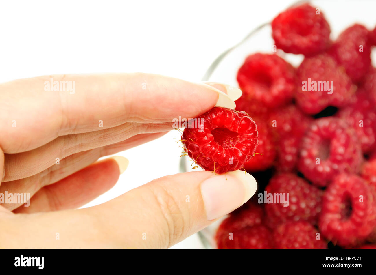 woman hand picking a fresh raspberry from a bowl Stock Photo - Alamy