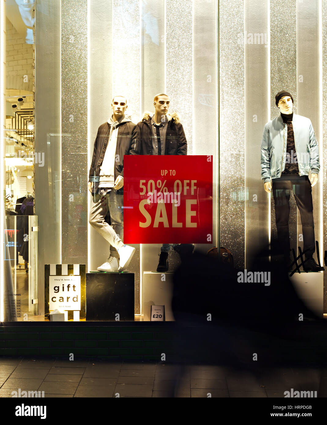 Male mannequins in a shop window display at night, with 50% off sign ...