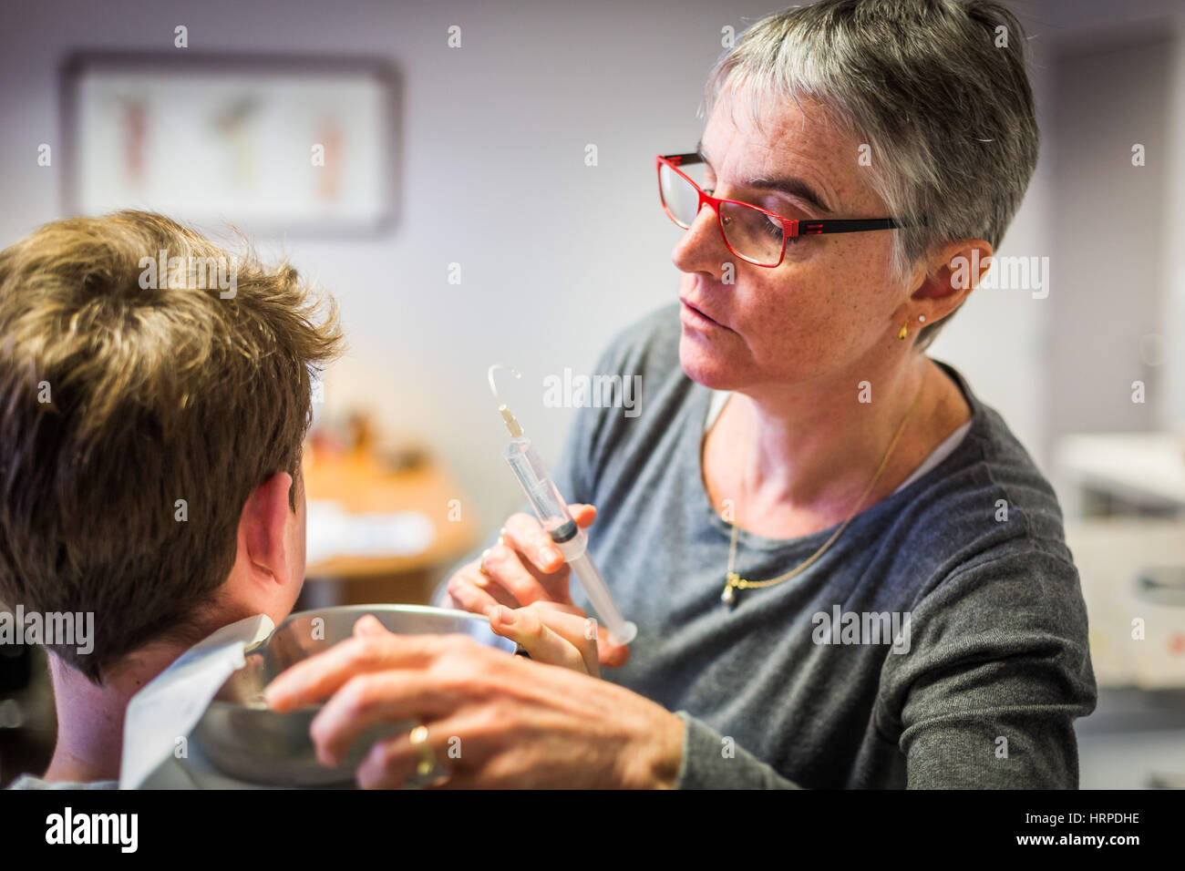 Here, doctor using a physiological serum syringe to clean the patient's ...